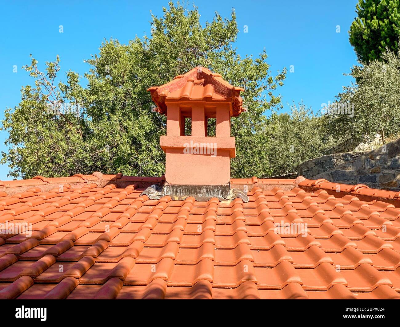 Orange chimney on the roof covered with orange tiles against a ...