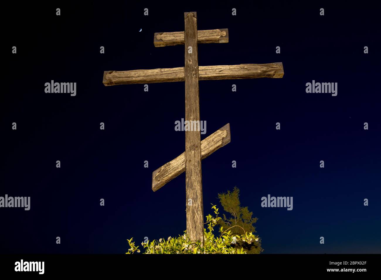 Huge wooden Orthodox eight-pointed cross against the sky after sunset ...