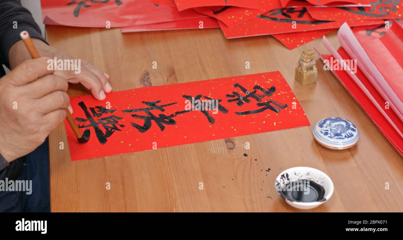 Old man pratice on writing Chinese calligraphy for lunar new year words ...