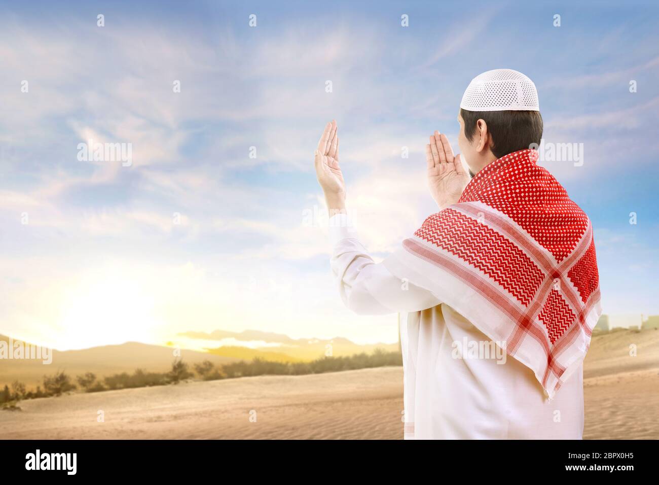 Rear view of asian muslim man with cap and turban standing and praying ...