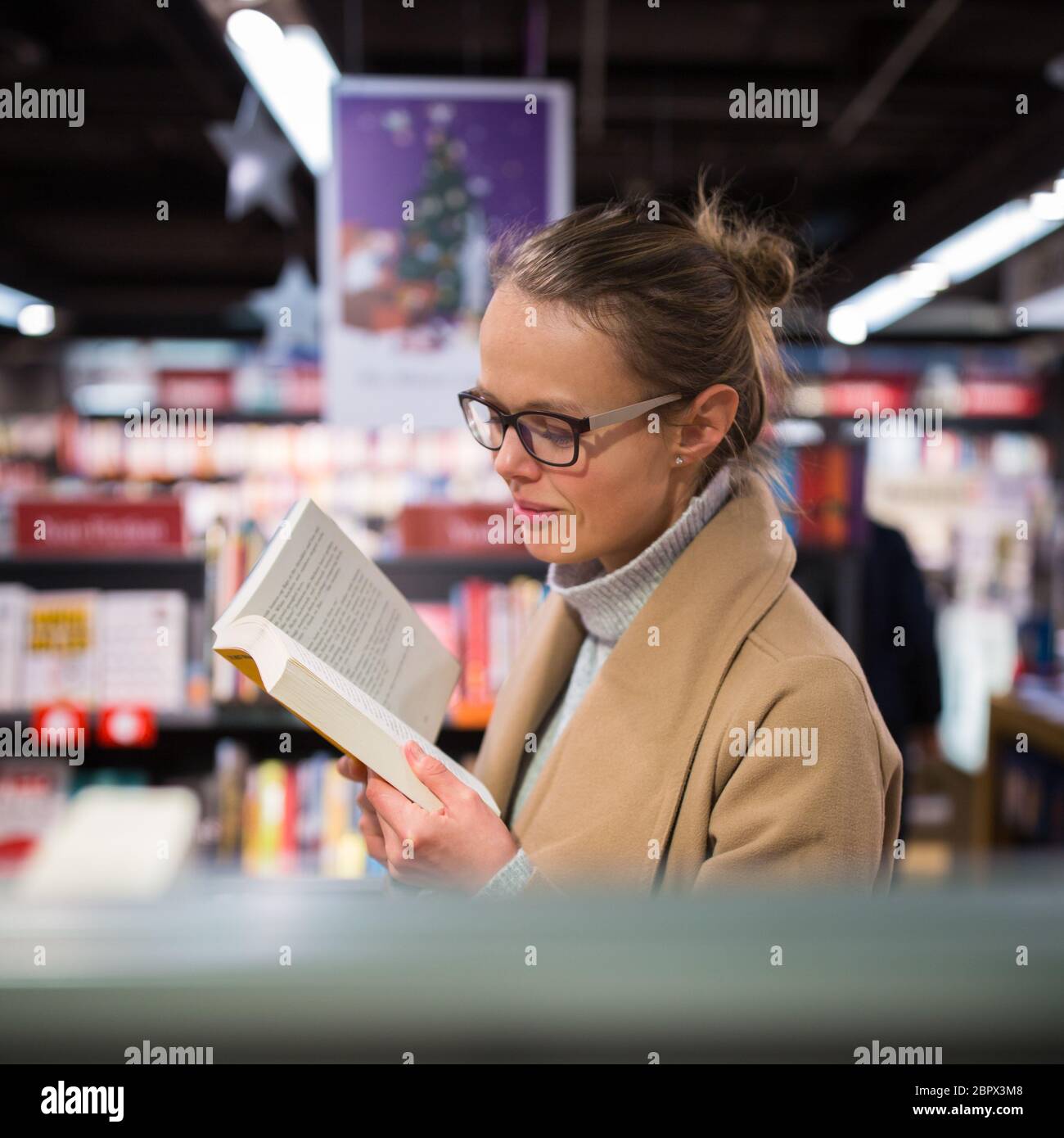 Pretty, young female choosing a good book to buy in a bookstore Stock ...