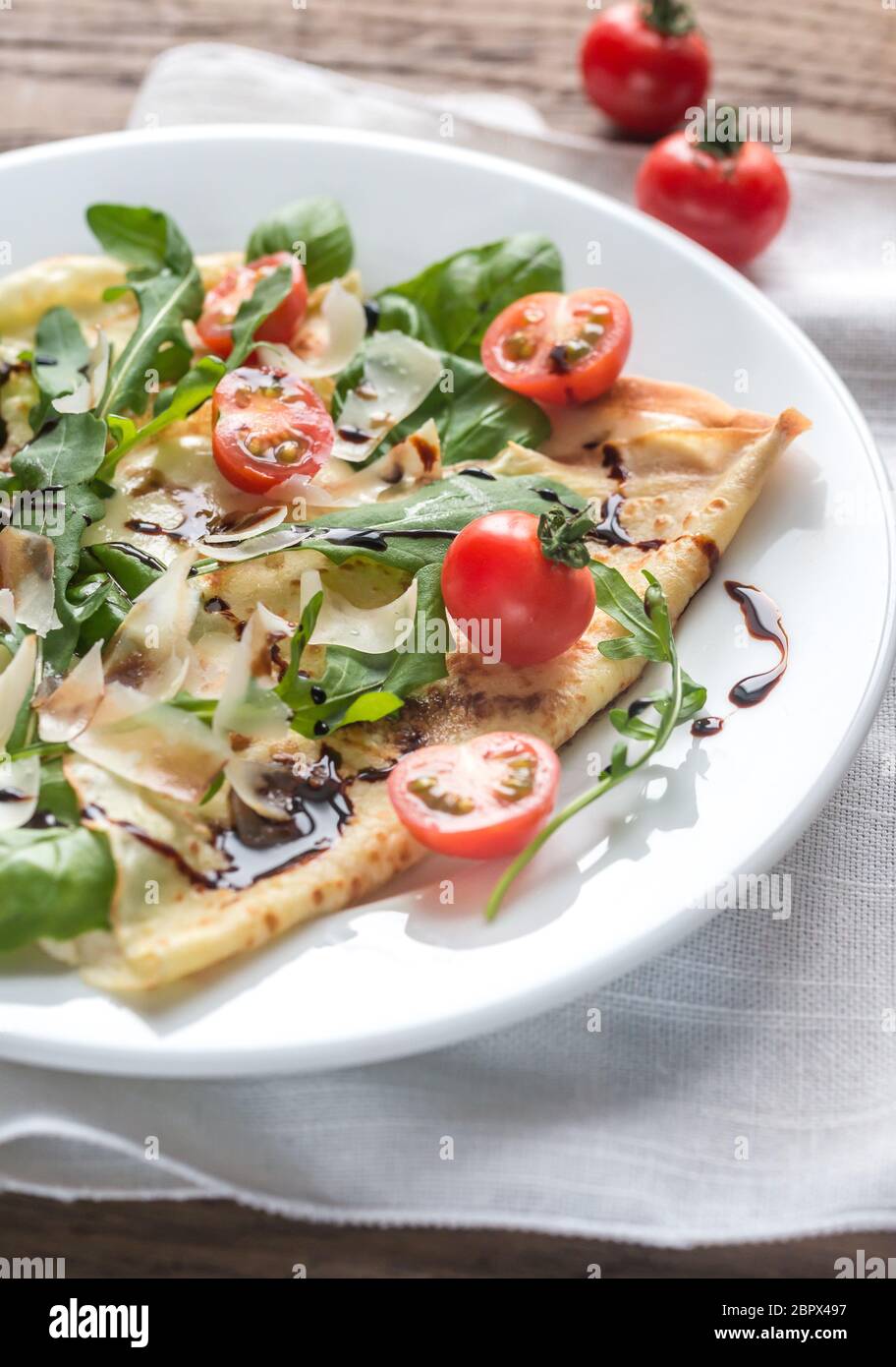 Crepes with cherry tomatoes, italian cheese and arugula on the plate ...