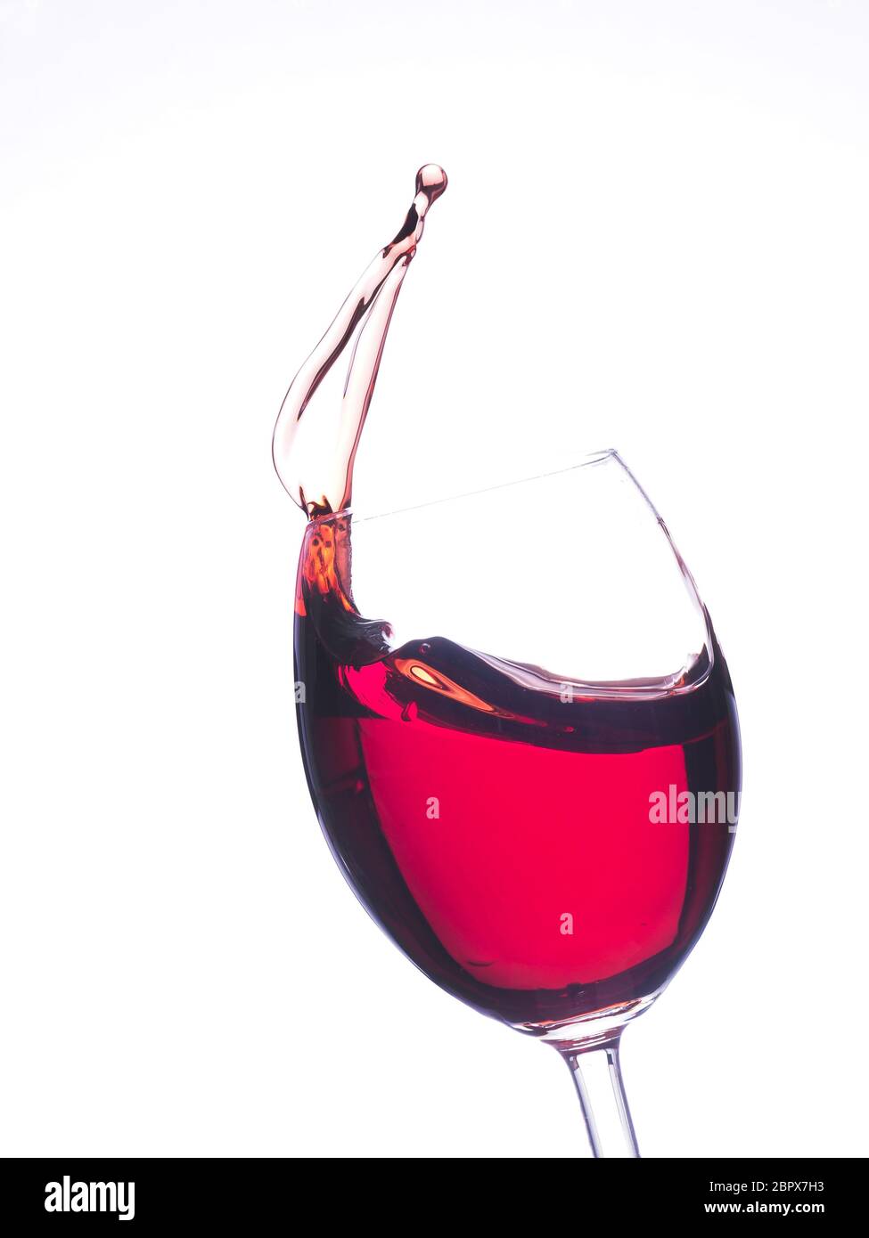 Splashing glass of red wine on a bright background Stock Photo - Alamy