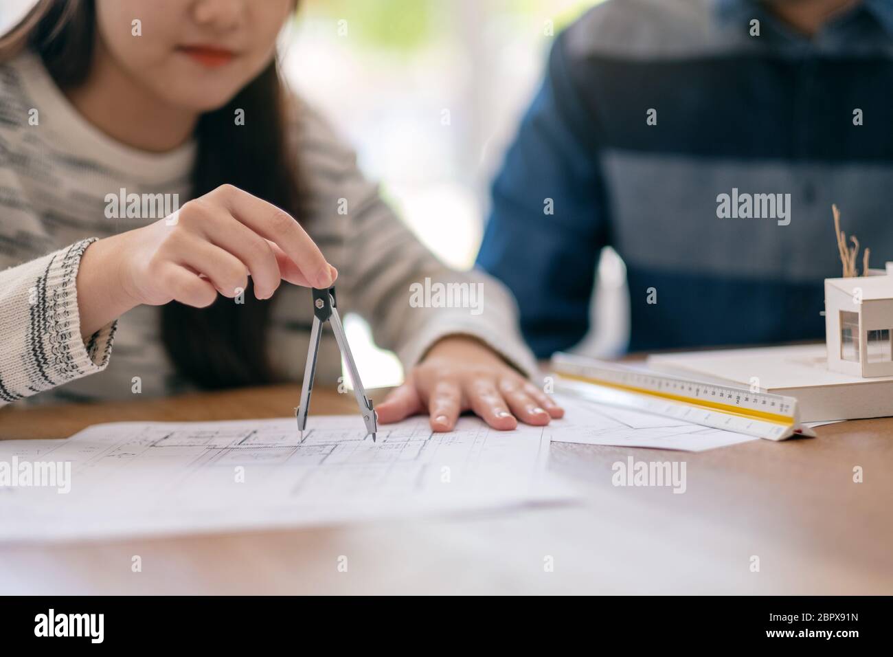 An architect using compass to draw and measure shop drawing in office ...