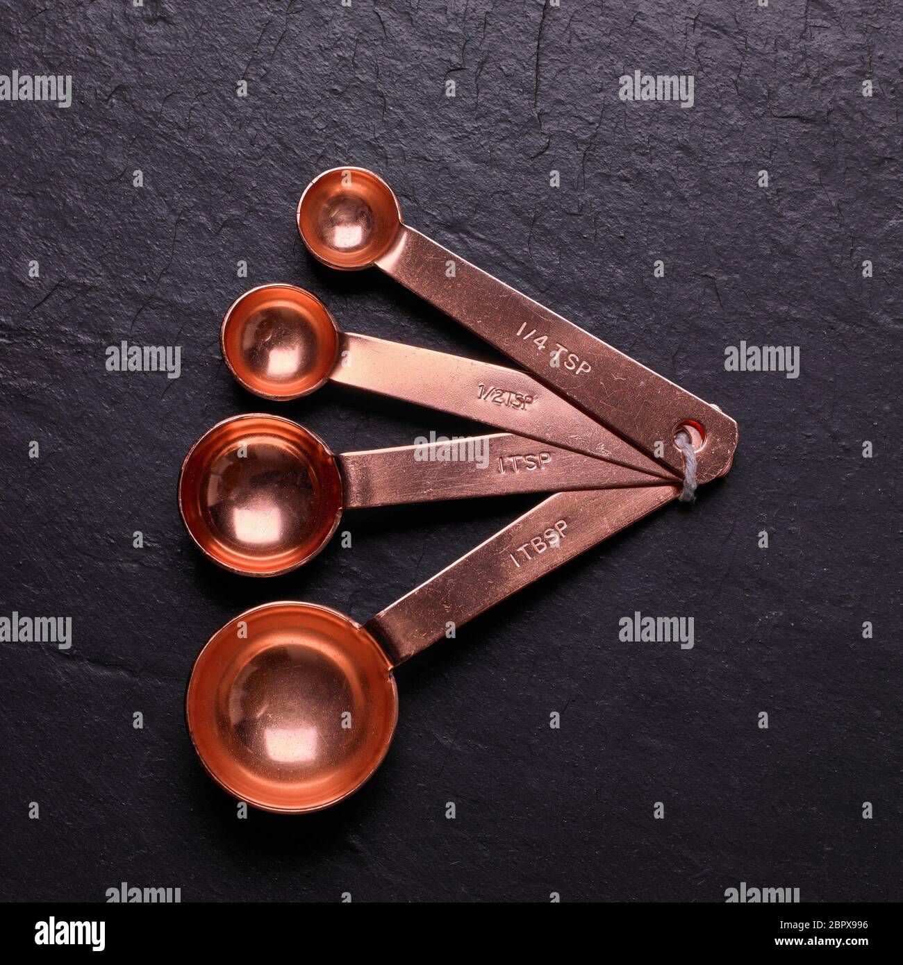 Copper measuring spoons on slate background Stock Photo - Alamy