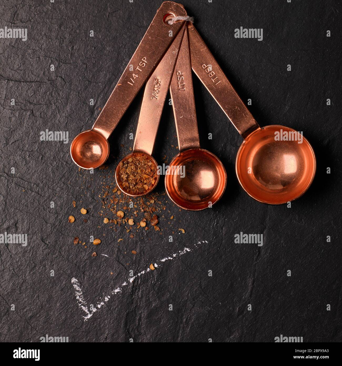 Copper measuring spoons on slate background with chalk tick mark Stock ...