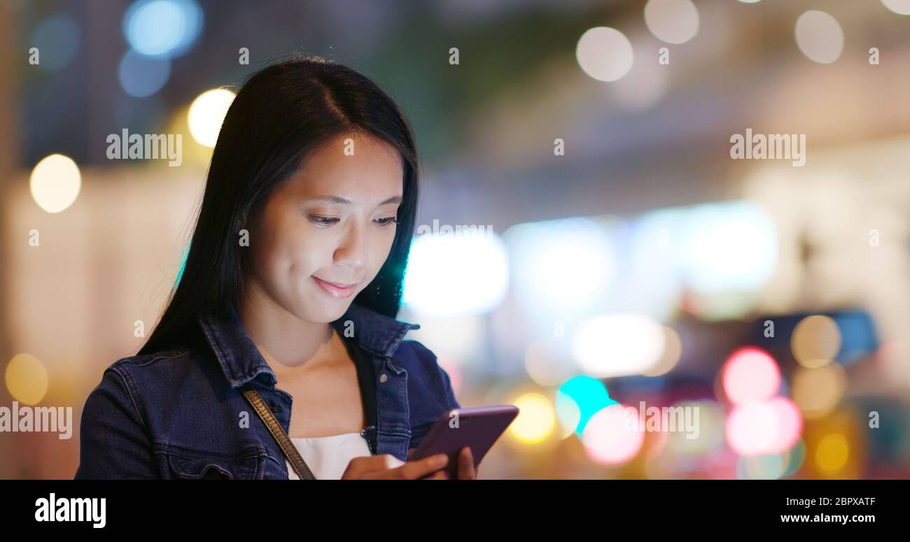 Woman use of mobile phone in city at night Stock Photo - Alamy