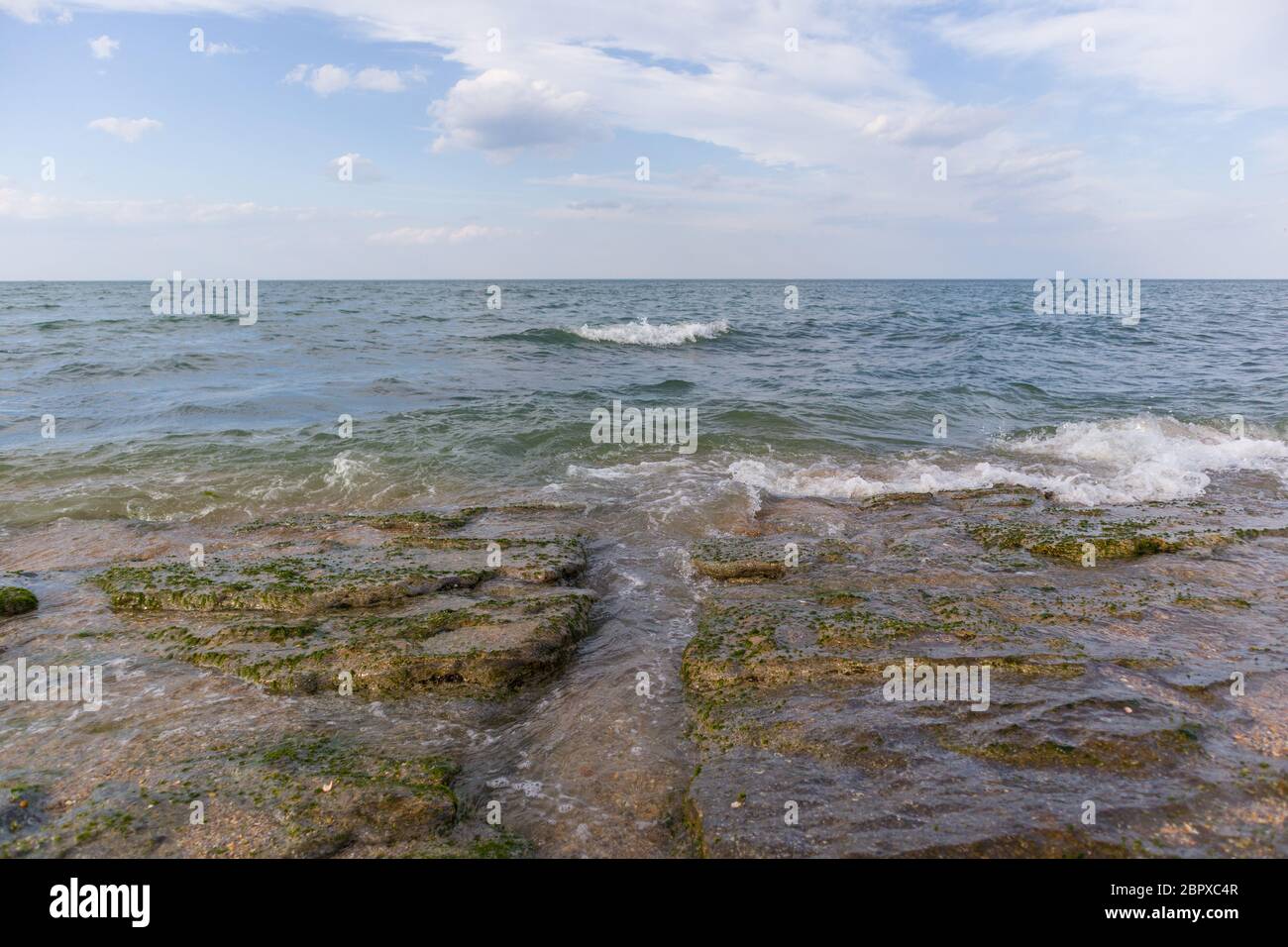 Natural strait between rocks, by the sea on a bright day with waves ...
