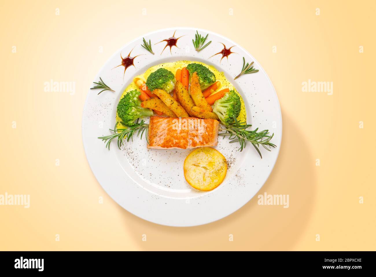 Salmon with curry sauce and fresh vegetables served in a plate. Top ...