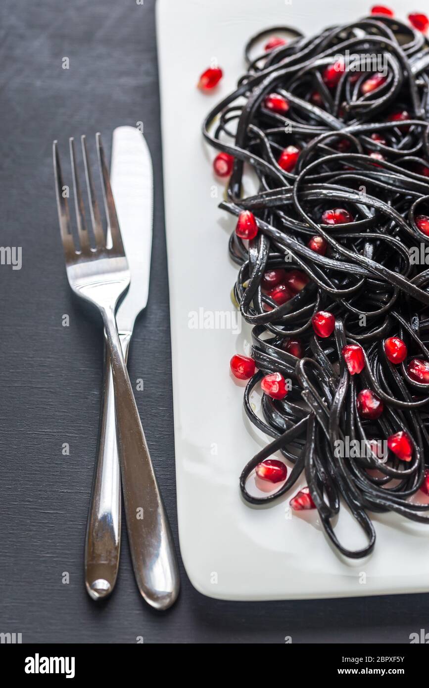 Black pasta with pomegranate seeds Stock Photo - Alamy