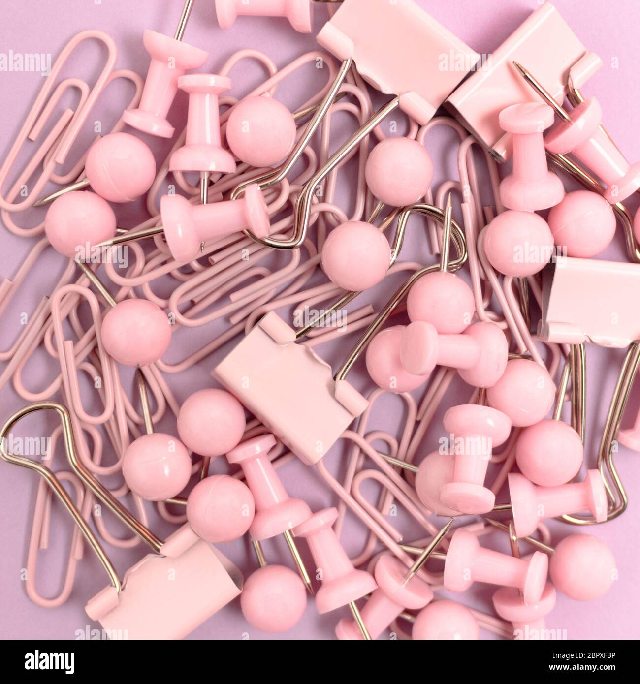 Texture made of paper clips and push pins on a pink pastel background ...