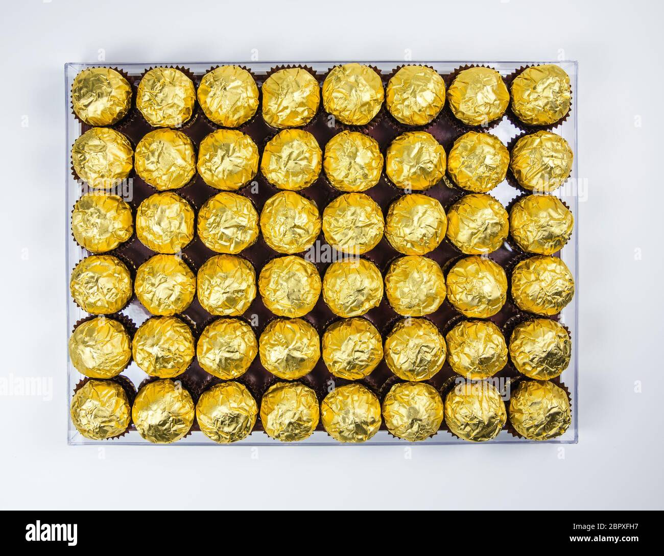 a lot of shiny golden chocolate wrapper in line on white background ...