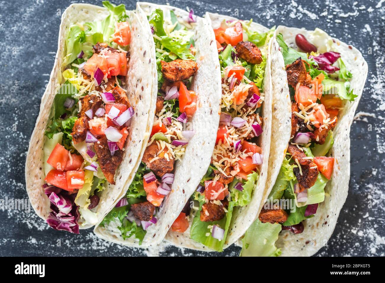 Four mexican tacos on a black background Stock Photo - Alamy
