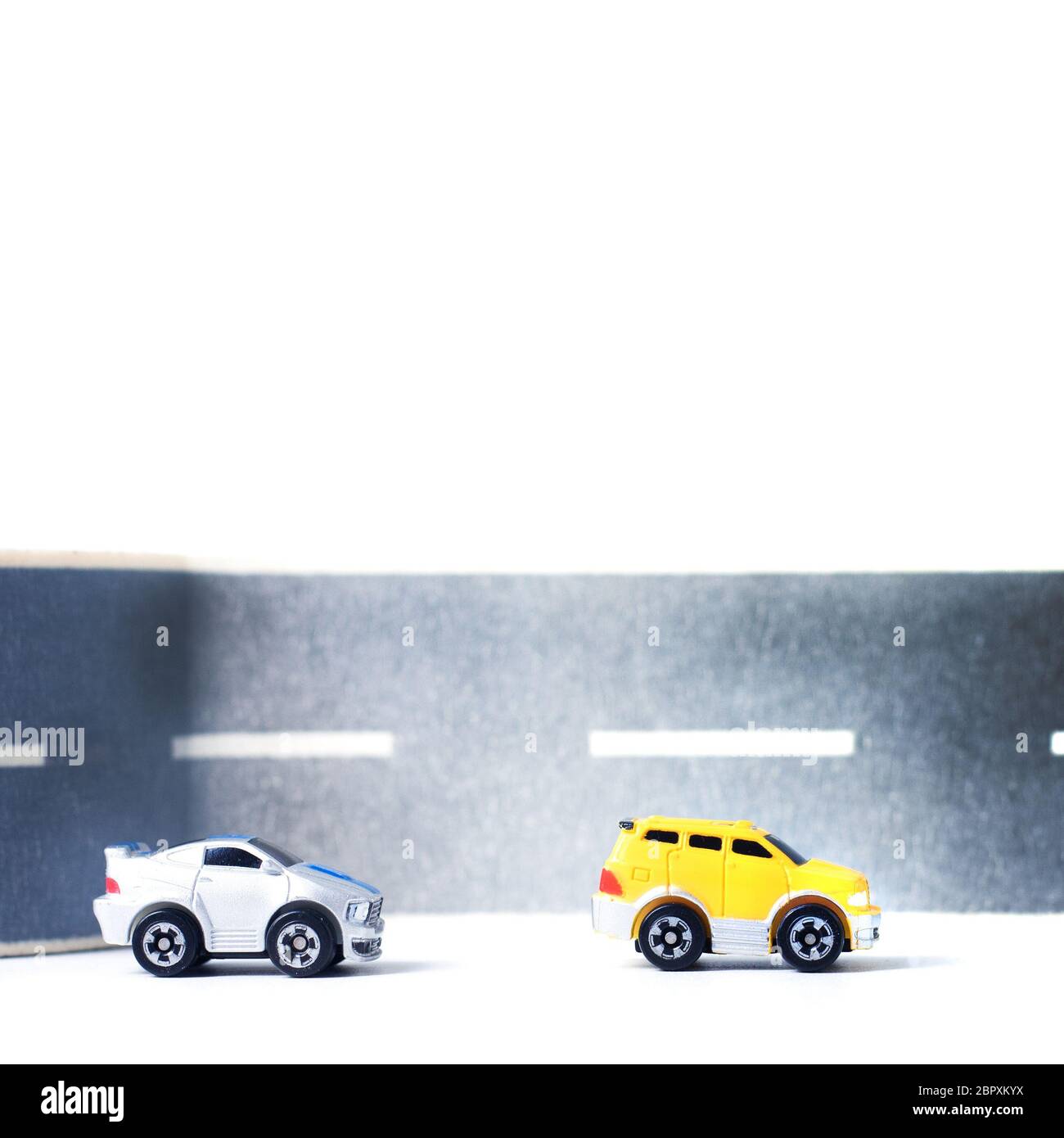 Two small cars on paper road on wite background. Traffic. Focus on grey ...