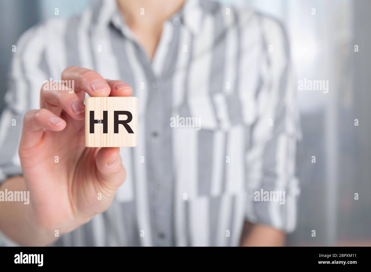 Hand of female holding wood cube block with letters HR. Human Resources ...