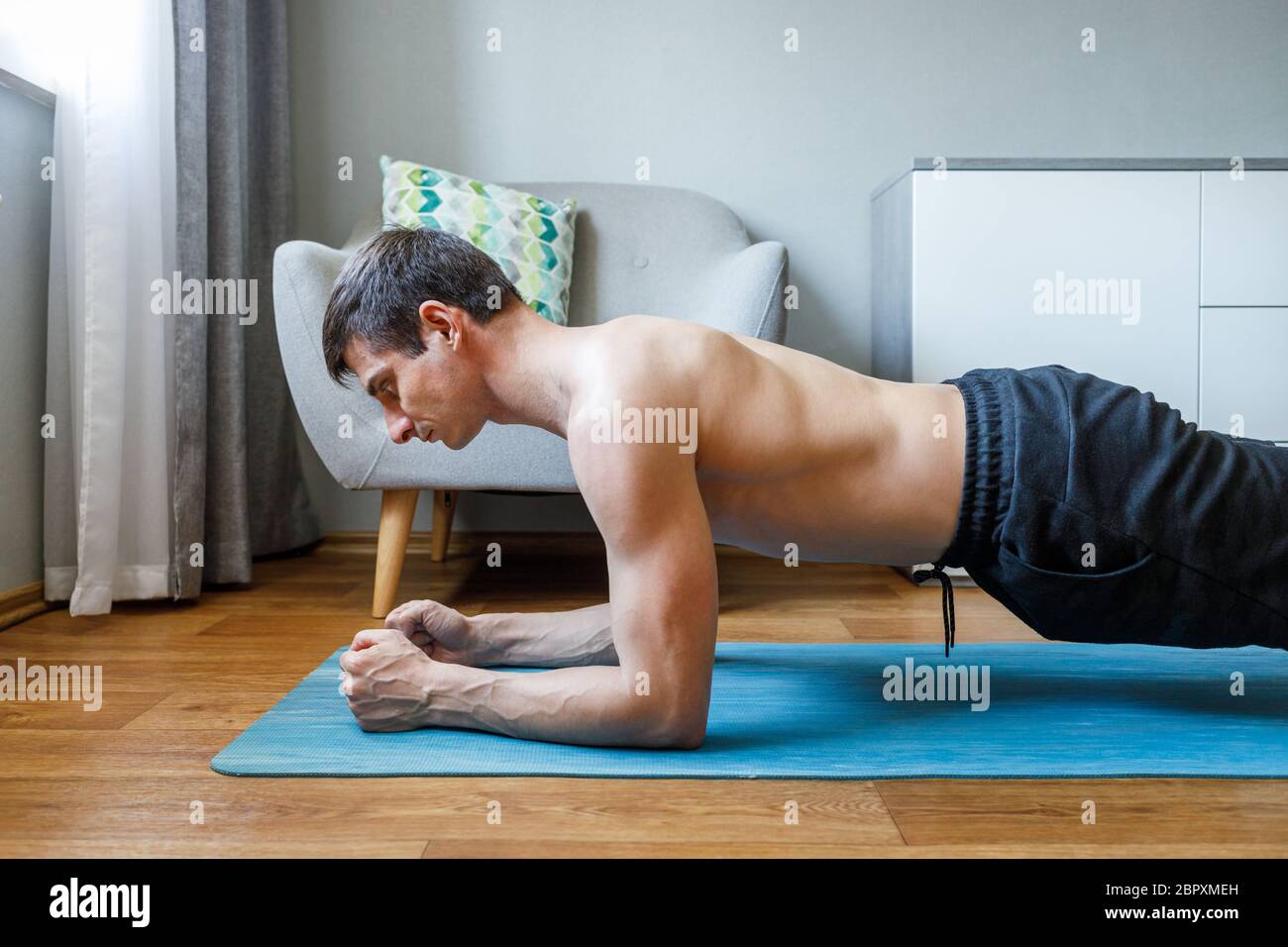 Man holding forearm plank pose doing yoga at home on quarantine Stock ...
