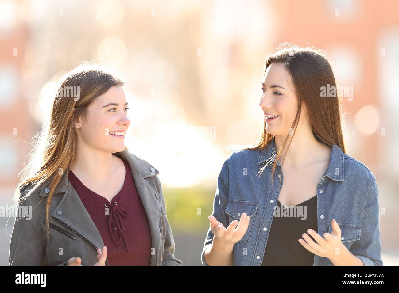 Front view of two young women walking and talking in the street Stock ...