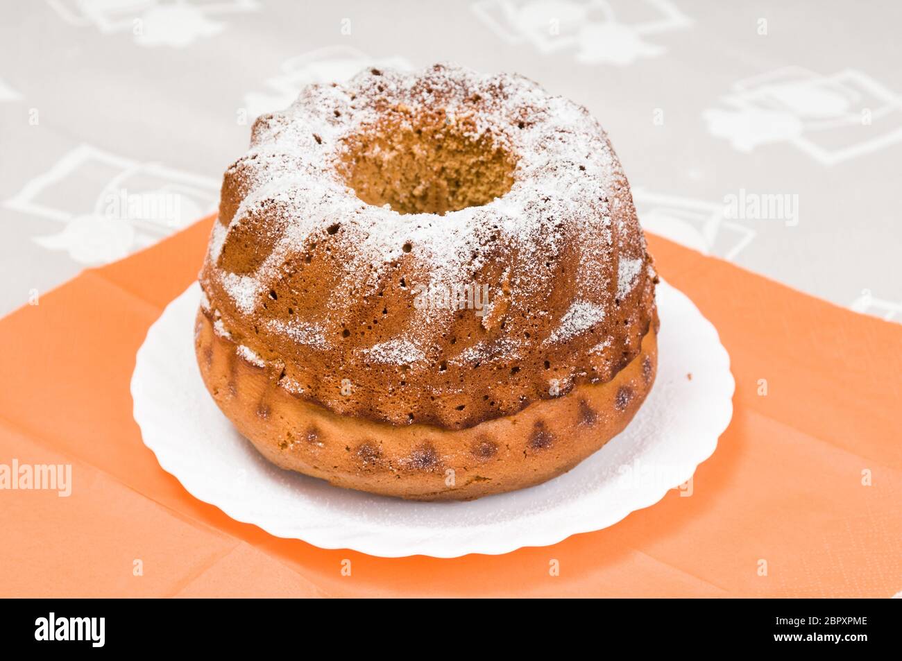 Homemade ring cake dusted with icing sugar on white plate Stock Photo ...