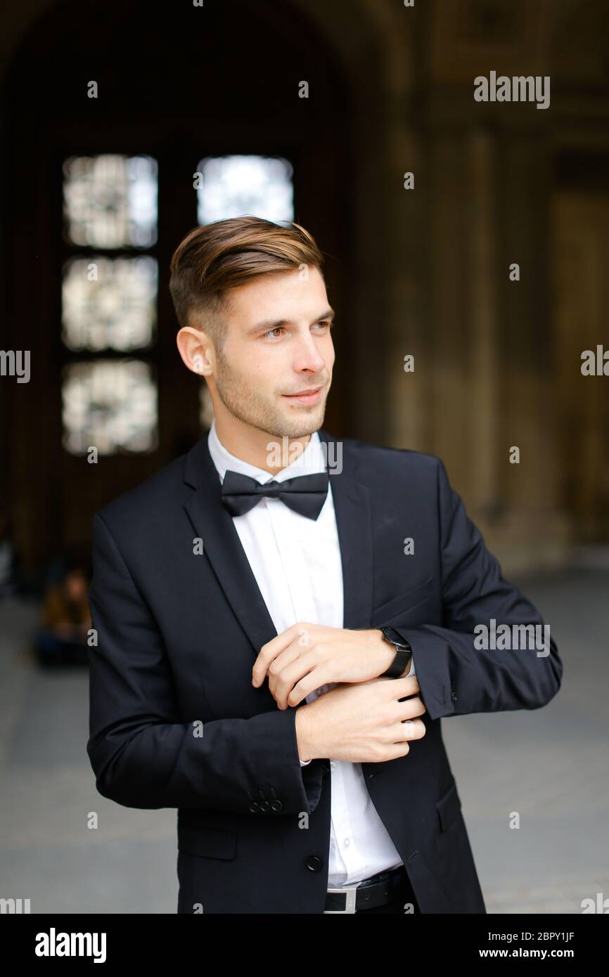 Young man standing and posing, wearing black suit and bow tie Stock ...