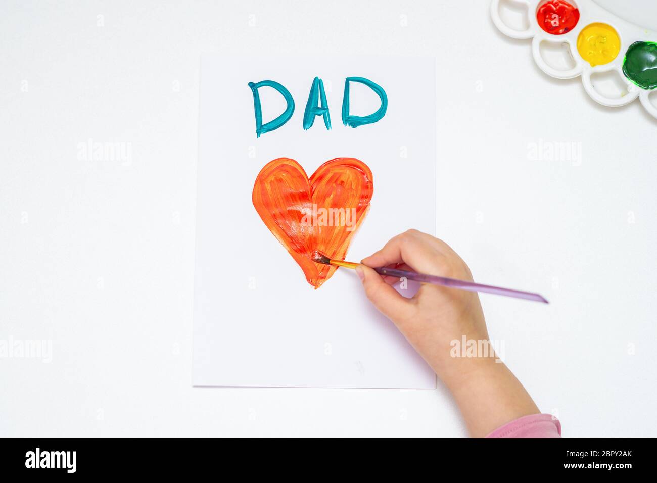 Top view of child's hand drawing red heart with word Dad greeting card ...