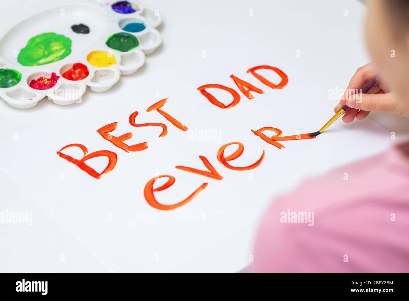 Hand of child drawing handwritten text Best Dad Ever on white paper ...