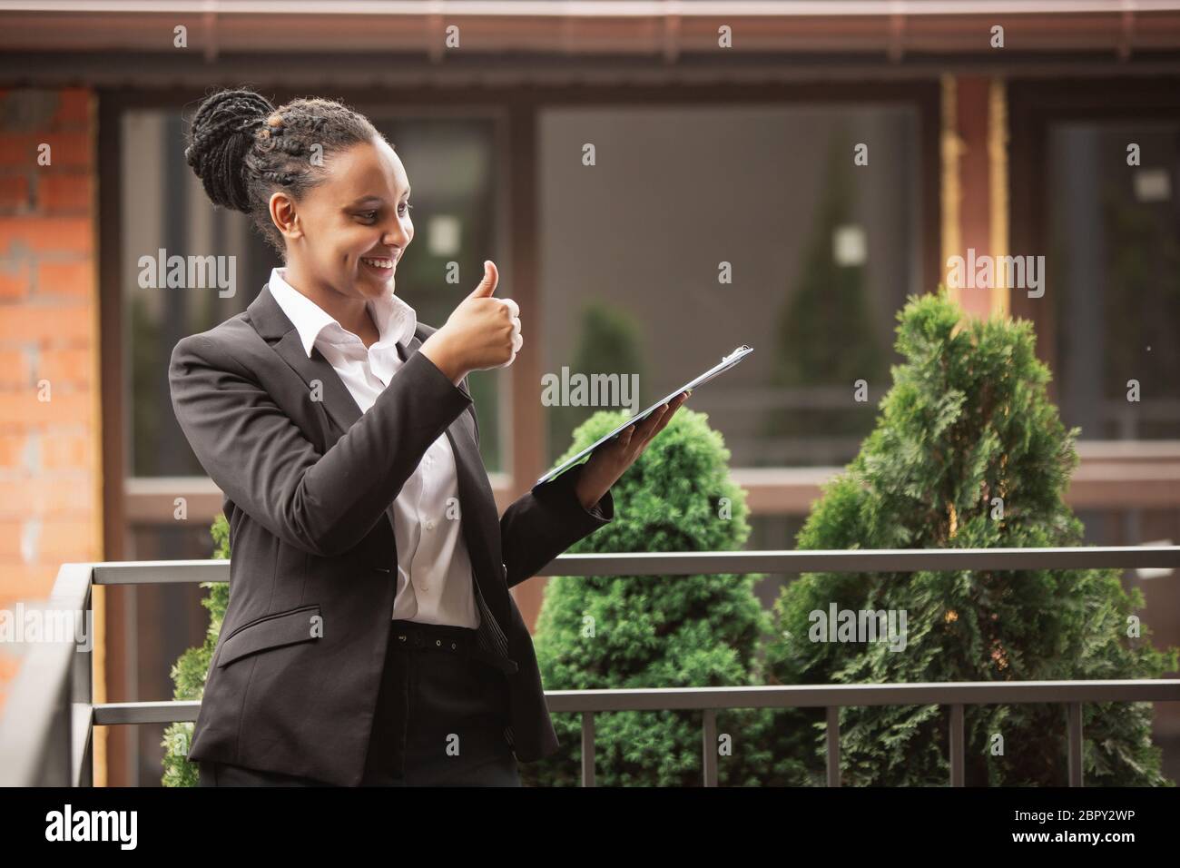 Paperwork, thumb up. African-american businesswoman in office attire ...
