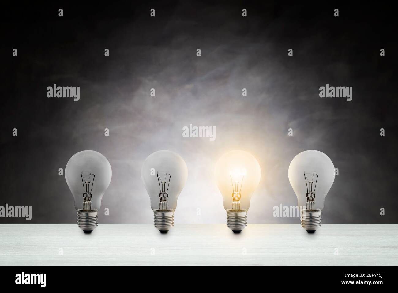 Concept of idea. Light bulb lit among unlit bulbs Stock Photo - Alamy