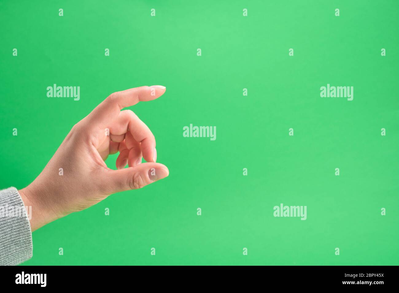 female hand on a green background, fingers in the gesture of holding ...