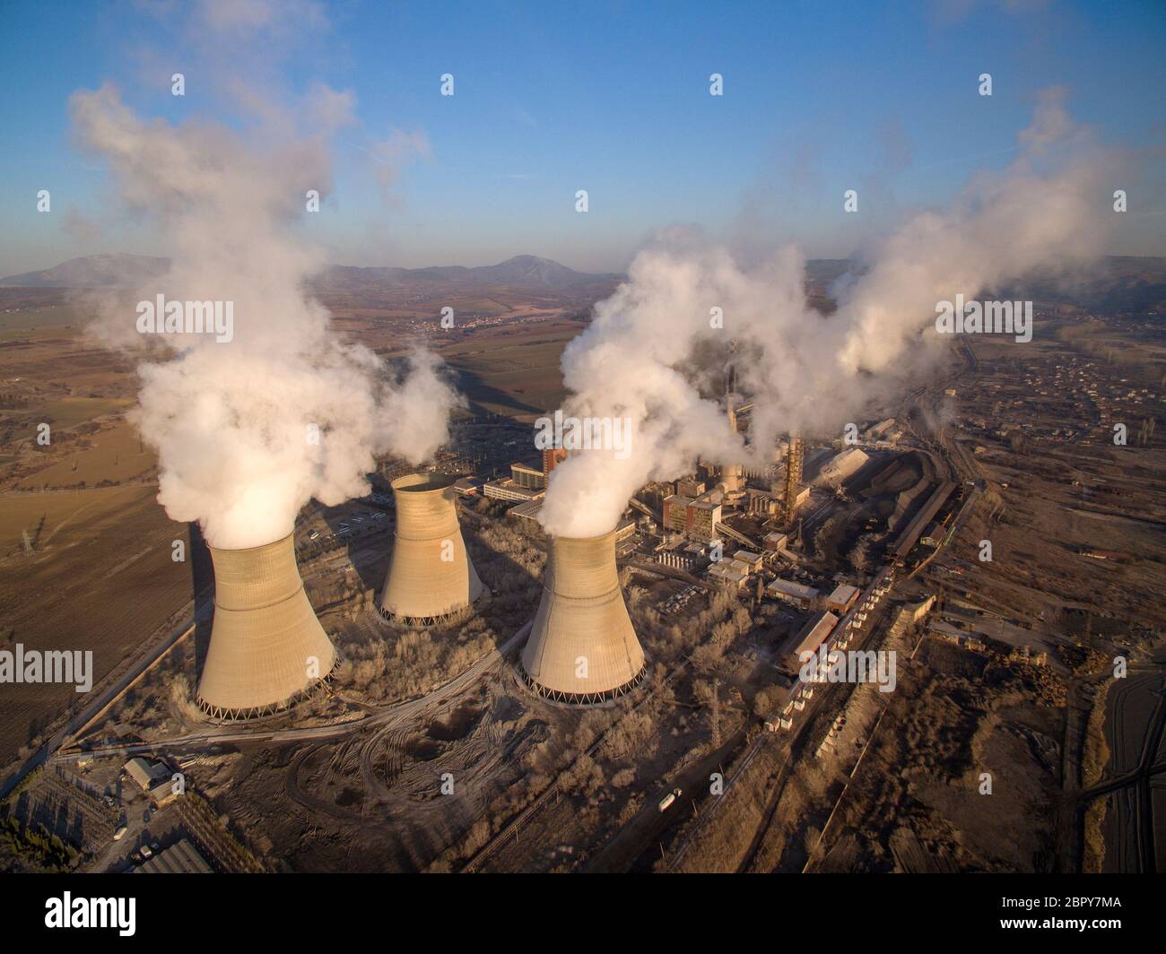 Aerial shot of coal-fired power plant and its cooling tower with steam ...