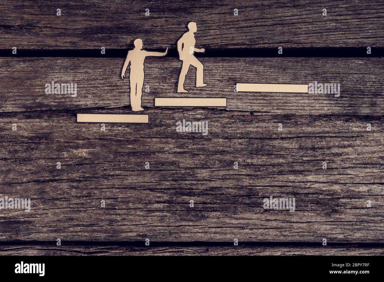 Cut outs of paper men with one giving a helping push from behind and ...
