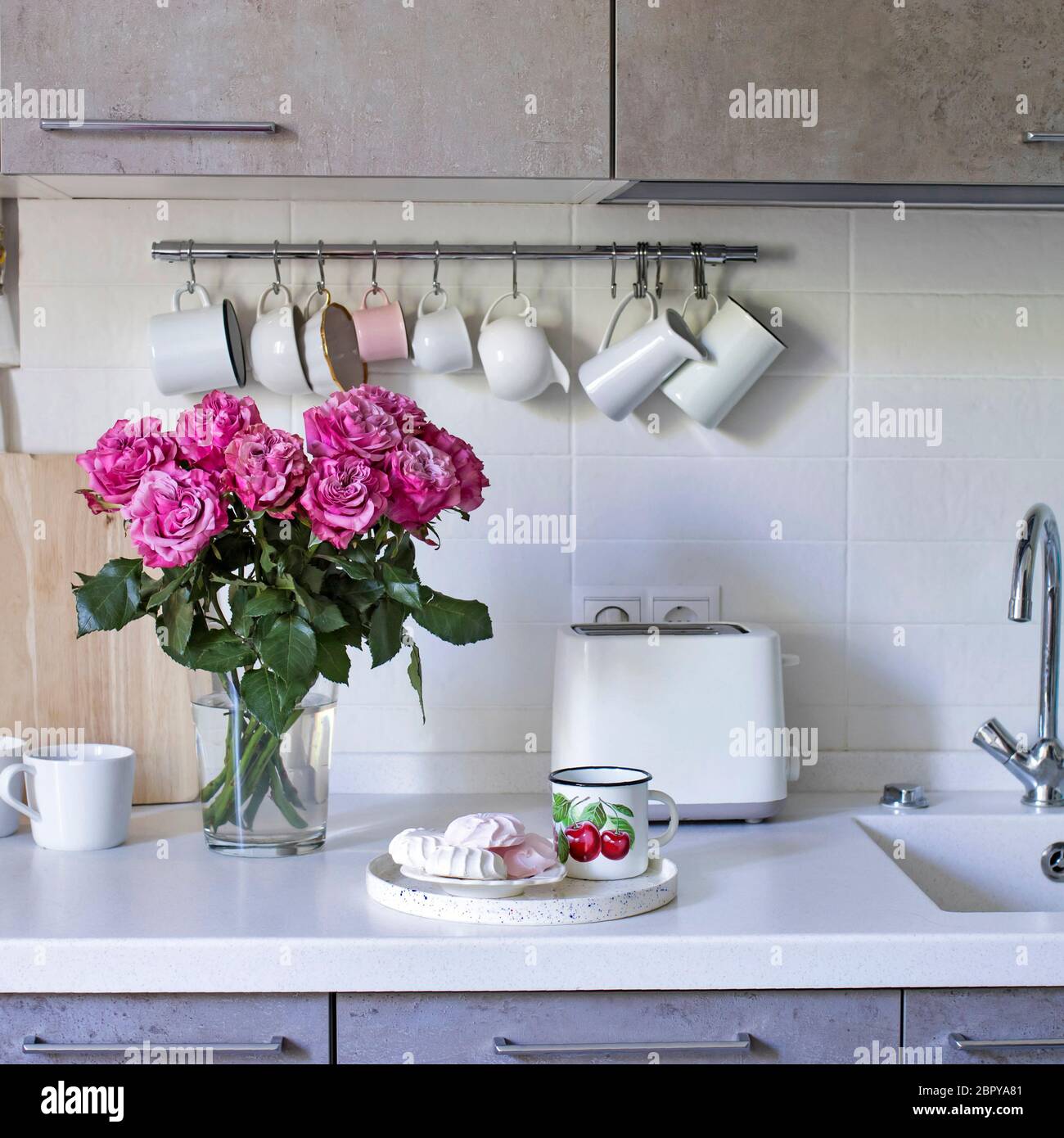 Kitchen in beige tones. Toaster. Mugs and milk jugs hang on hooks. Sink ...