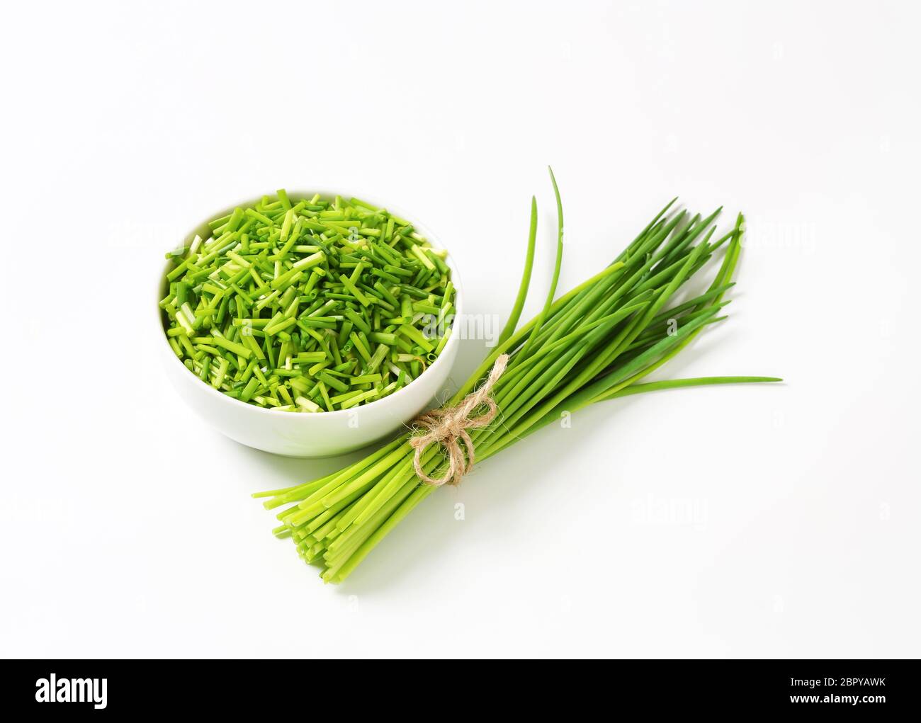 Bowl of fresh chopped chives and bundle of chives next to it Stock ...