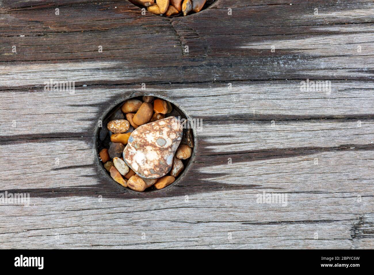 Small pebbles caught in the holes in a boat ramp on the beach at low ...