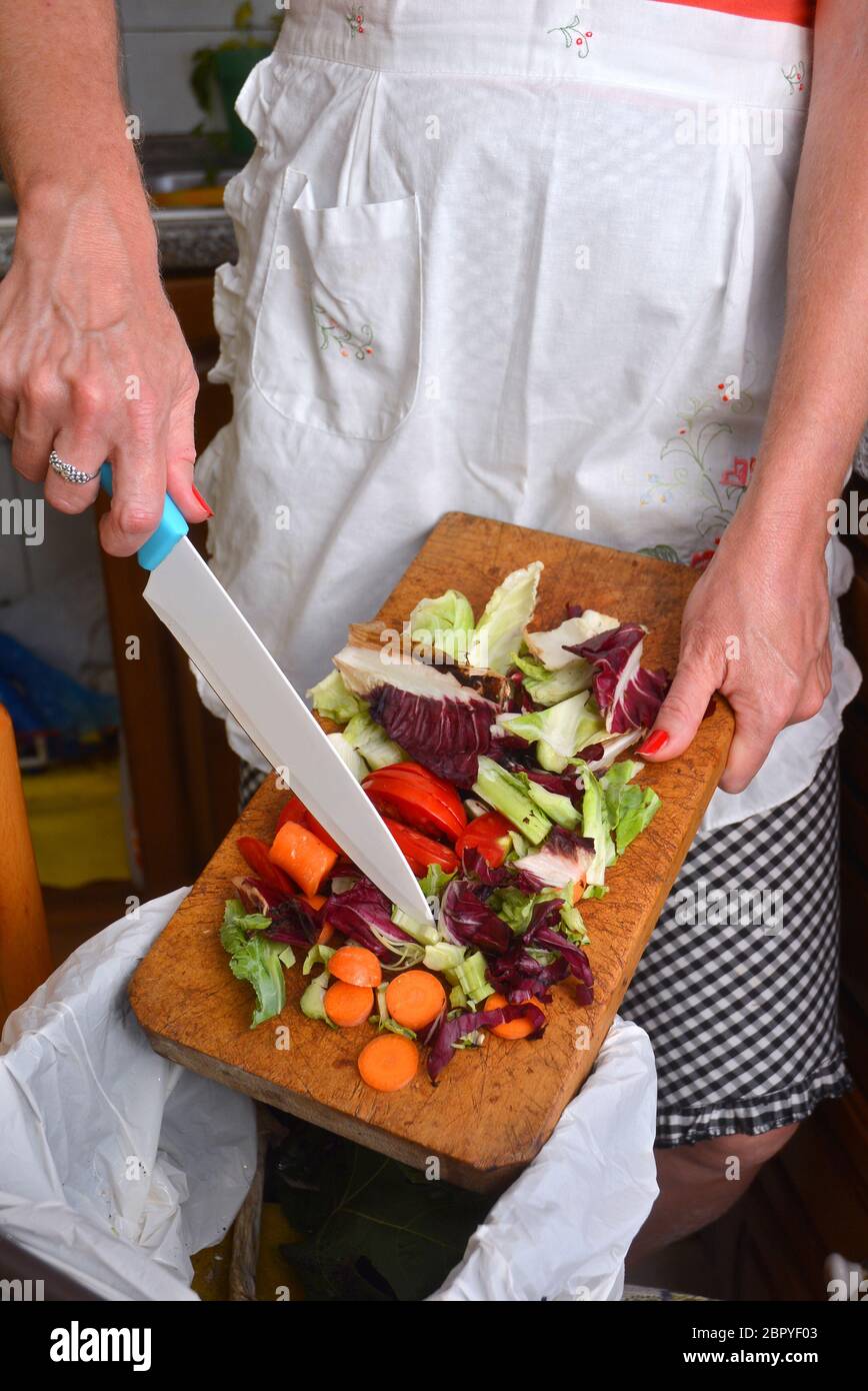 Detail of a female hand disposing of organic waste in a proper bin with ...