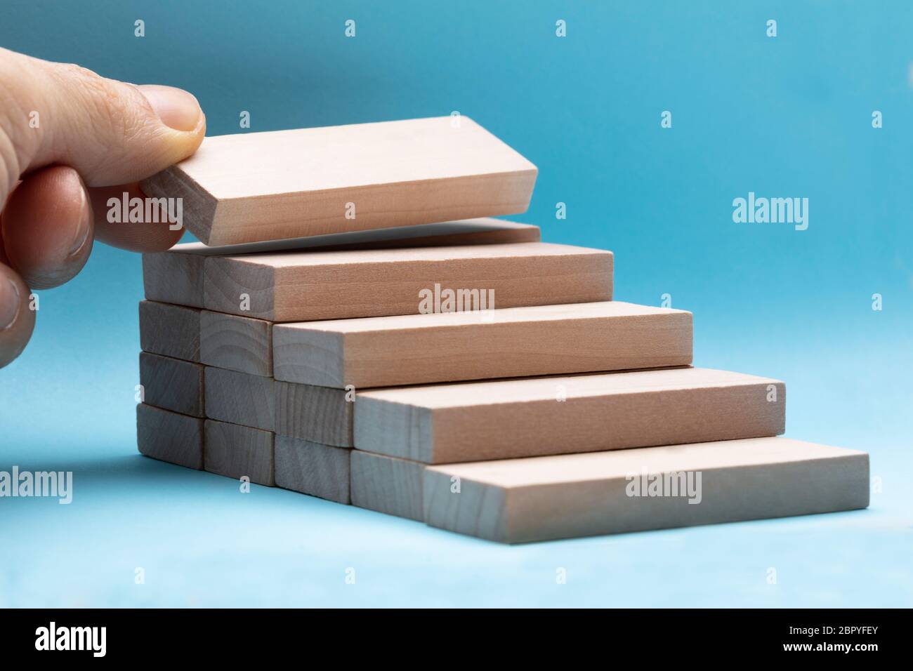 Man's Hand Arranging Wooden Block Stacking As Step On Blue Background ...