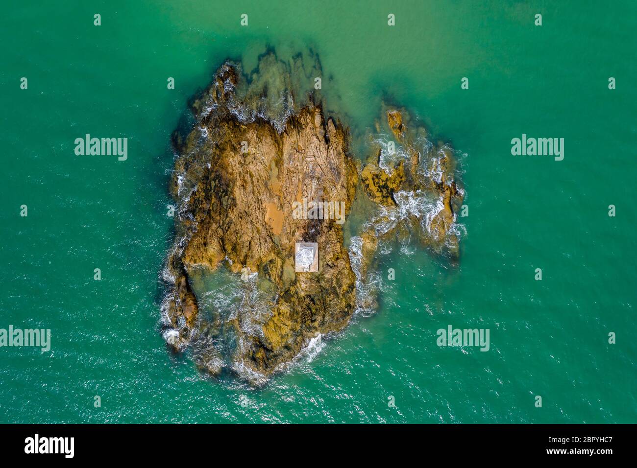 Top down aerial view of a small lighthouse on offshore rocks in a ...