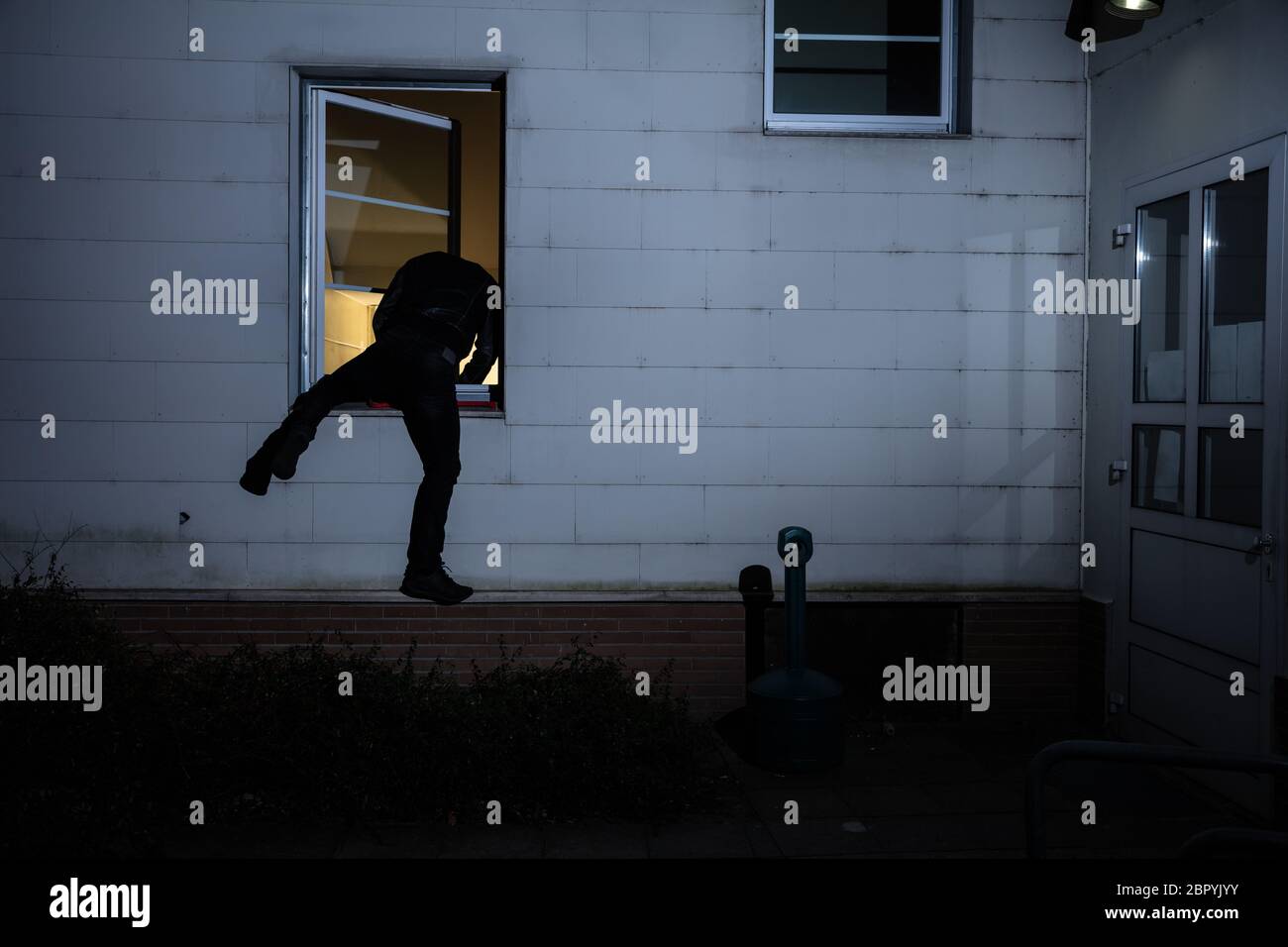 Rear View Of A Burglar Entering In A House Through A Window Stock Photo ...