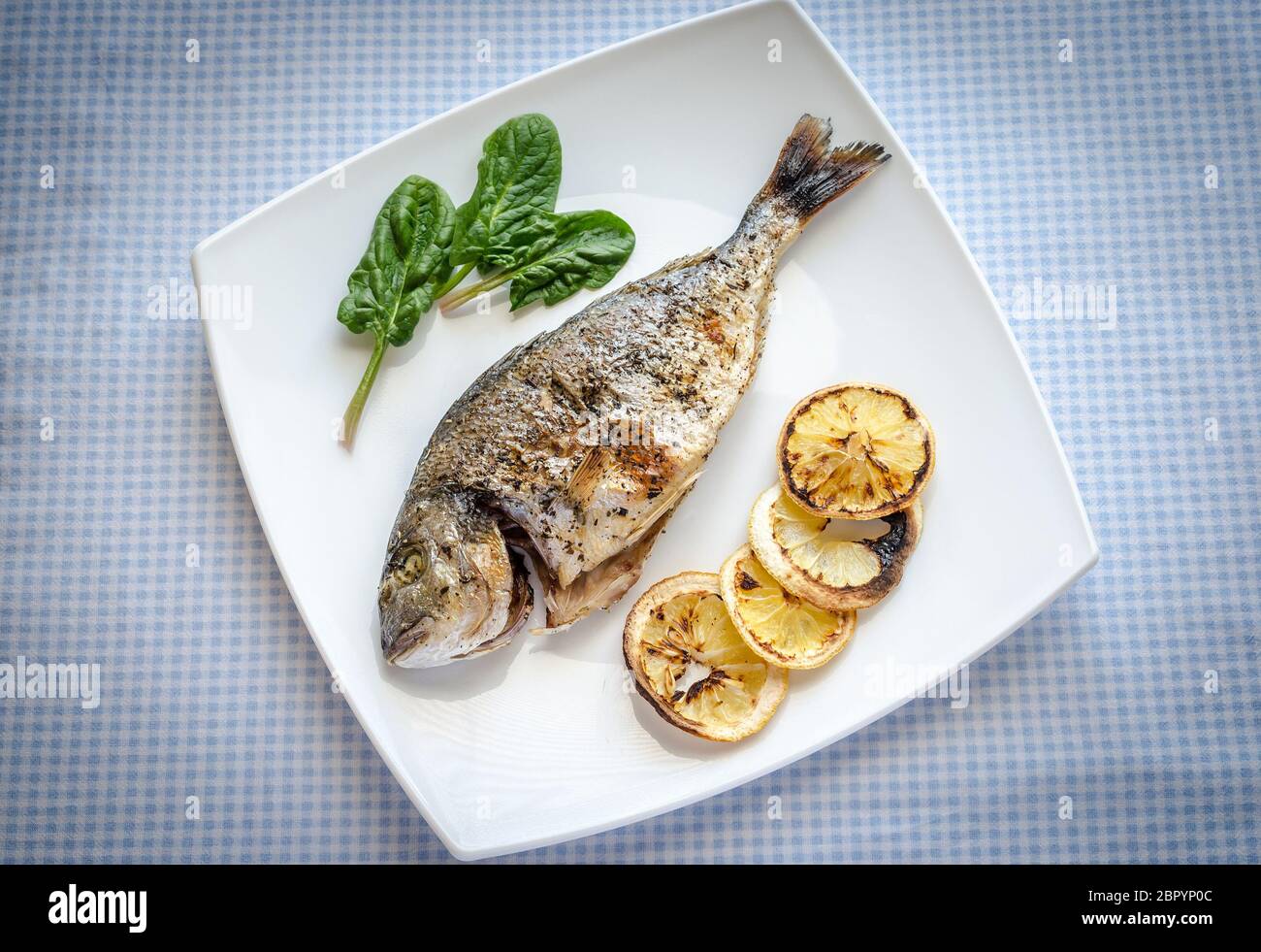 Grilled dorada fish with lemon and spinach Stock Photo - Alamy