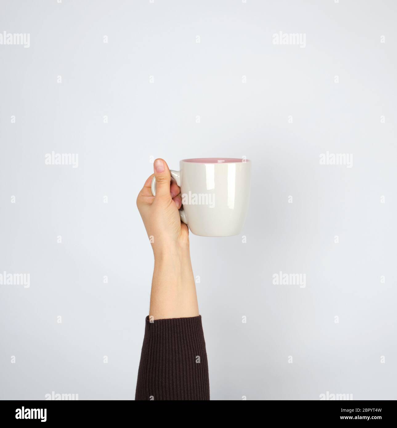 gray ceramic cup in female hand on a white background, hand raised up ...