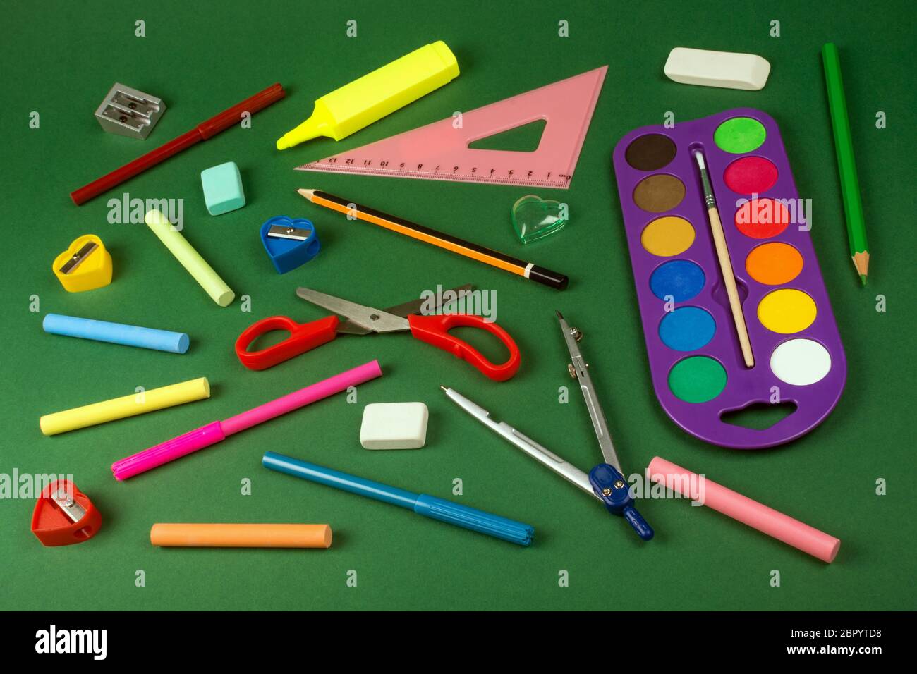 Different school supplies on green background, education or back to ...