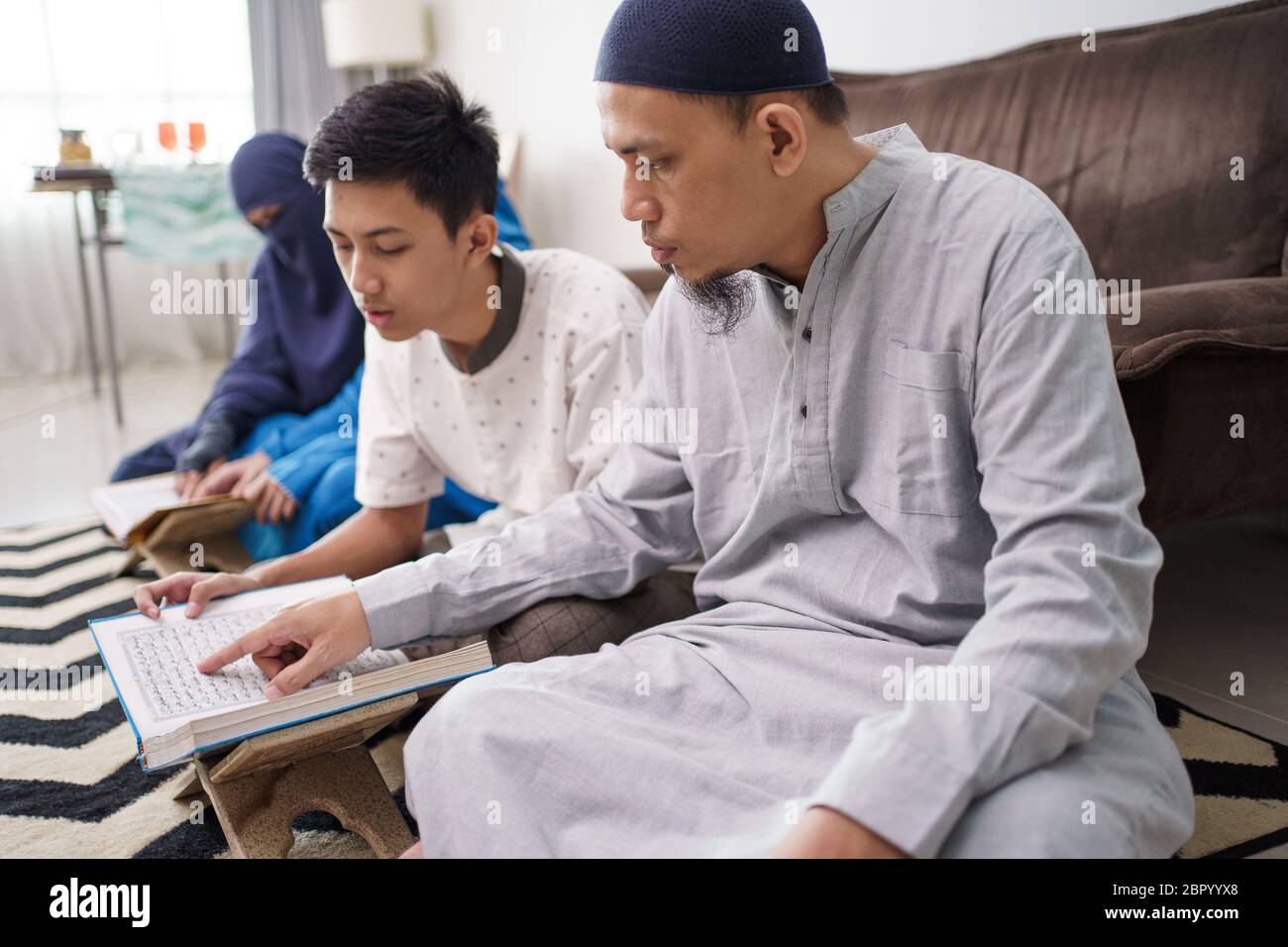 portrait of muslim family reading quran together in livingroom Stock ...