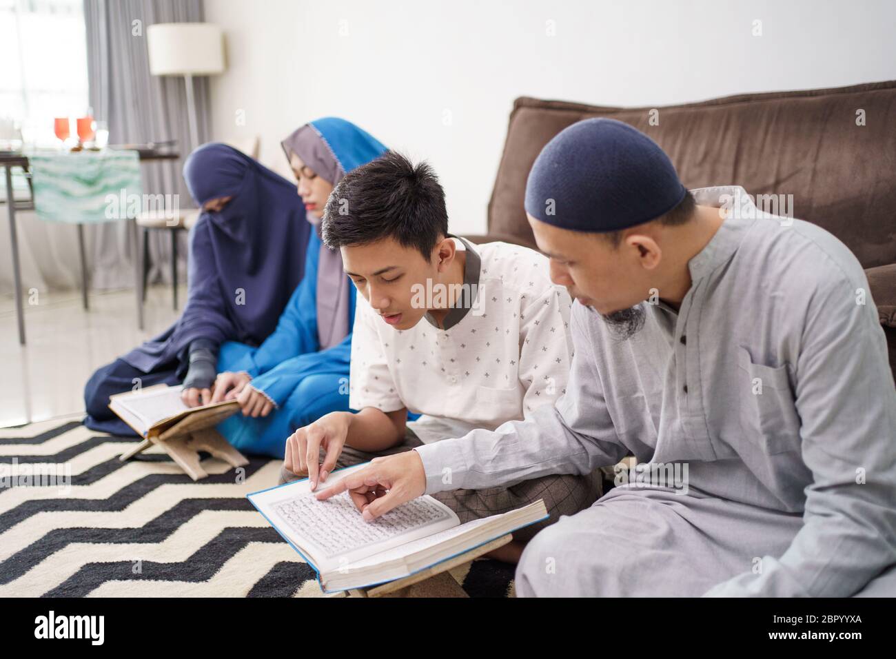 portrait of muslim family reading quran together in livingroom Stock ...