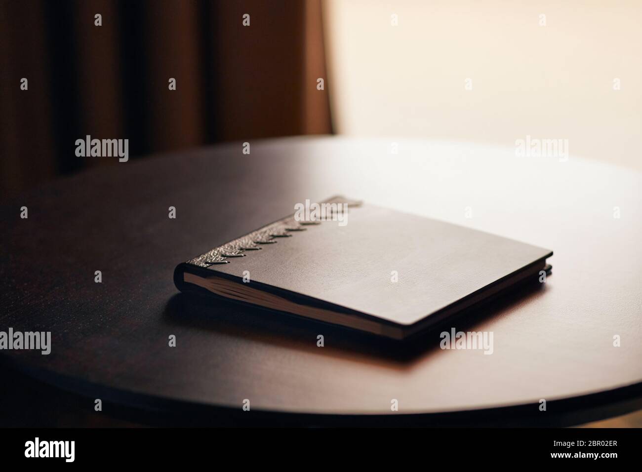 Note book with hard wooden cover on table by the window in natural ...