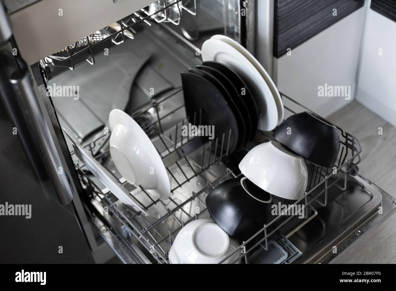 Loading dirty dishes in the dishwasher close up Stock Photo - Alamy