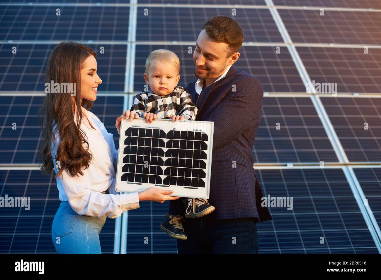 Young happy family on the background of solar panels. A man, woman and ...