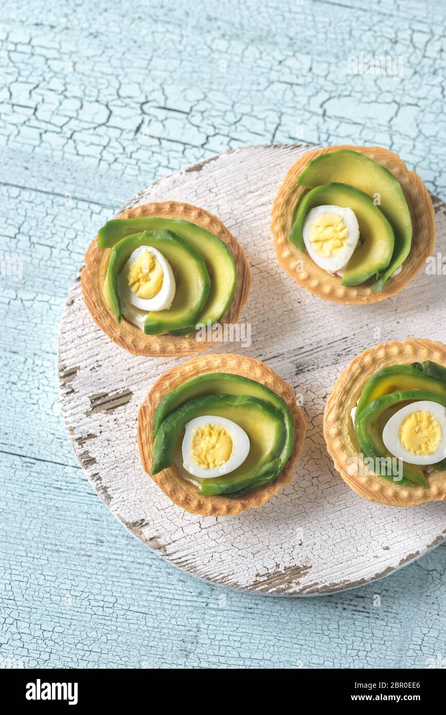 Tartlets with cream cheese, avocado and quail eggs Stock Photo - Alamy
