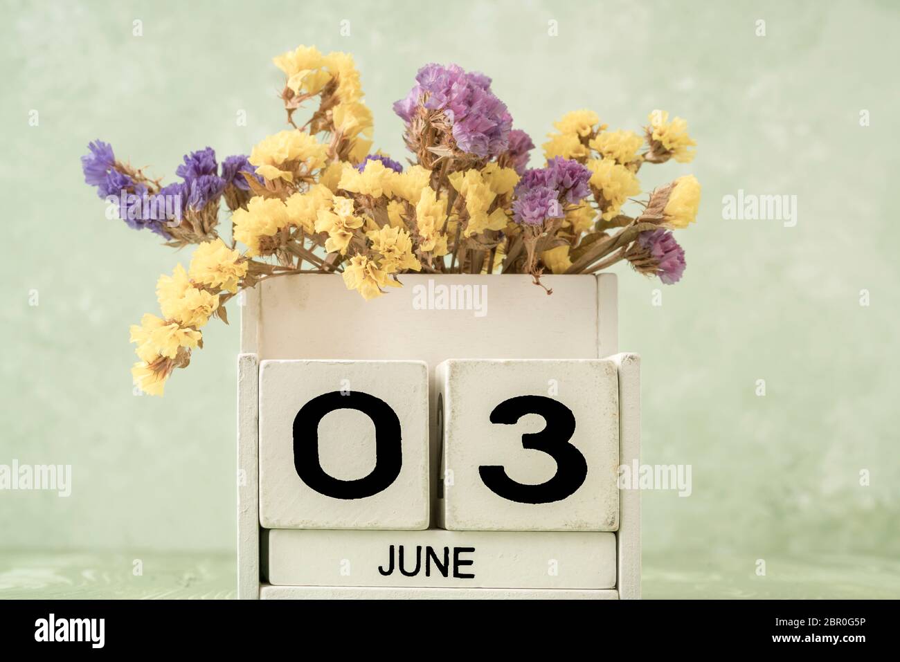 White cube calendar for june decorated with flowers over green ...