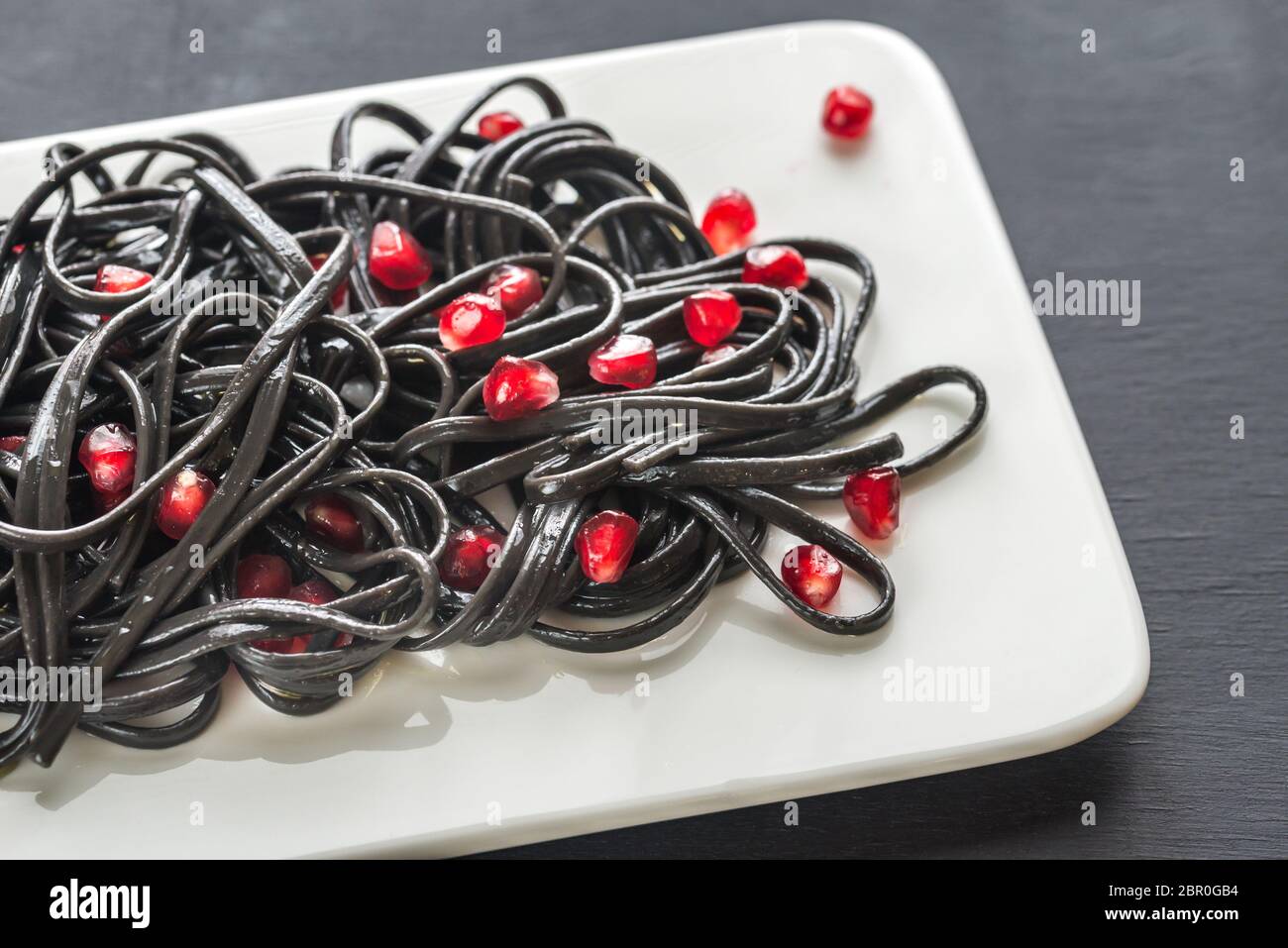 Black pasta with pomegranate seeds Stock Photo - Alamy