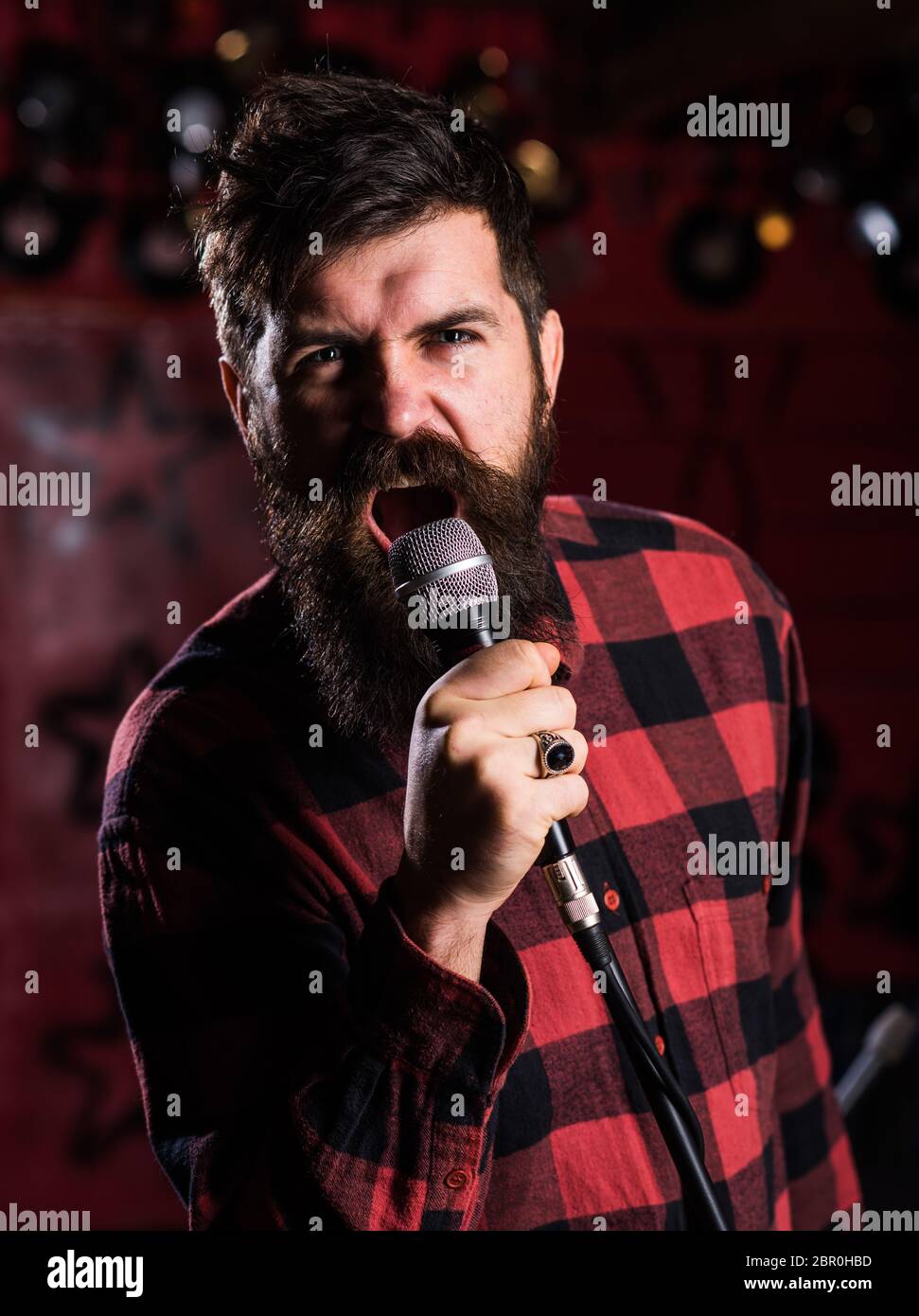 Man with agressive face holds microphone, singing song, karaoke club ...