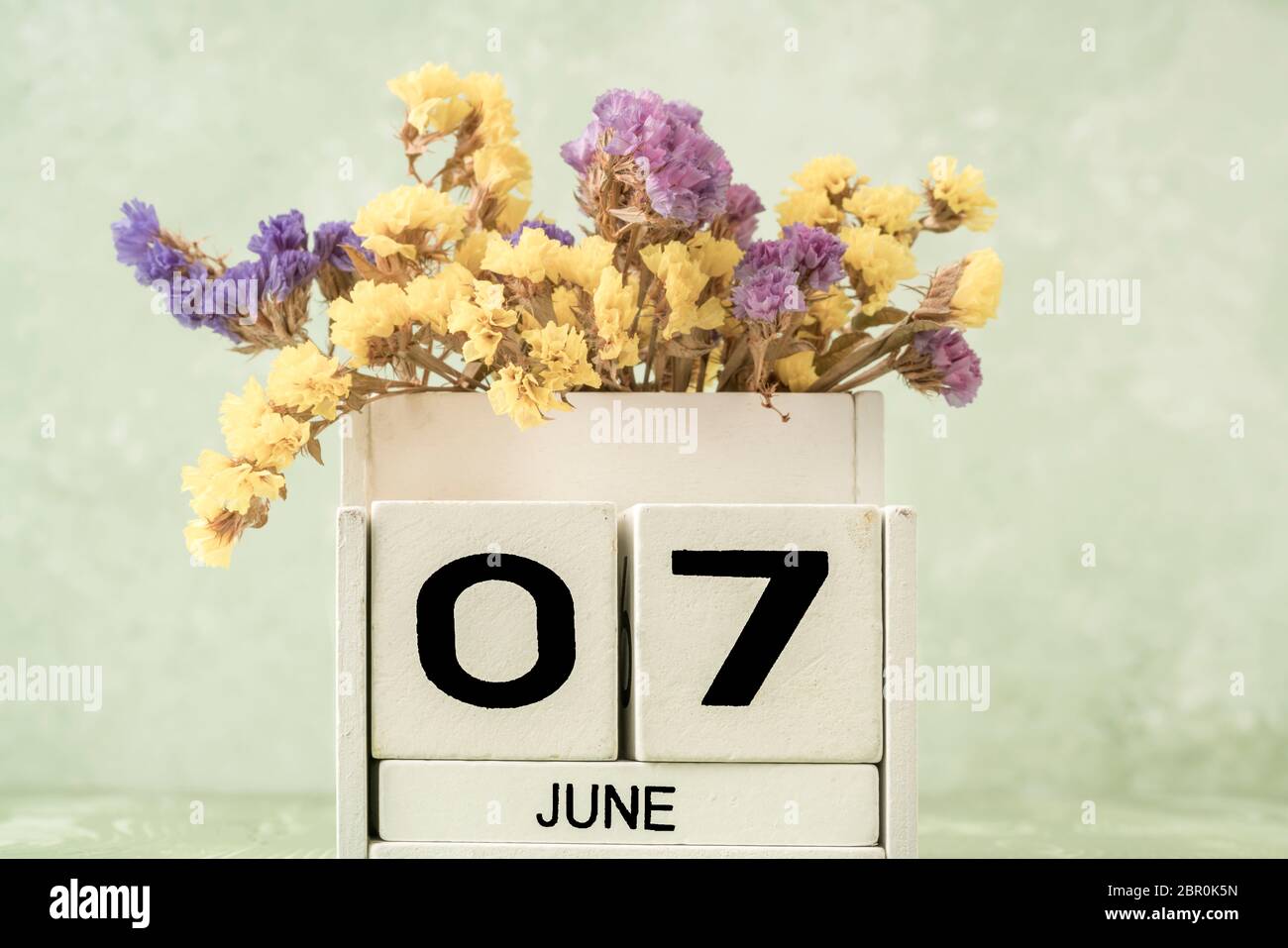 White cube calendar for june decorated with flowers over green ...